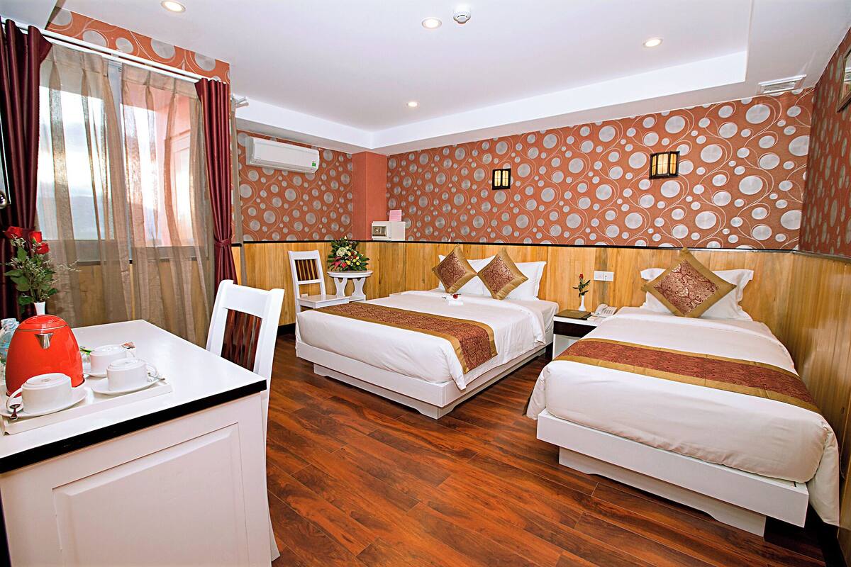 Quarto de hotel com duas camas, uma mesa e uma cadeira.