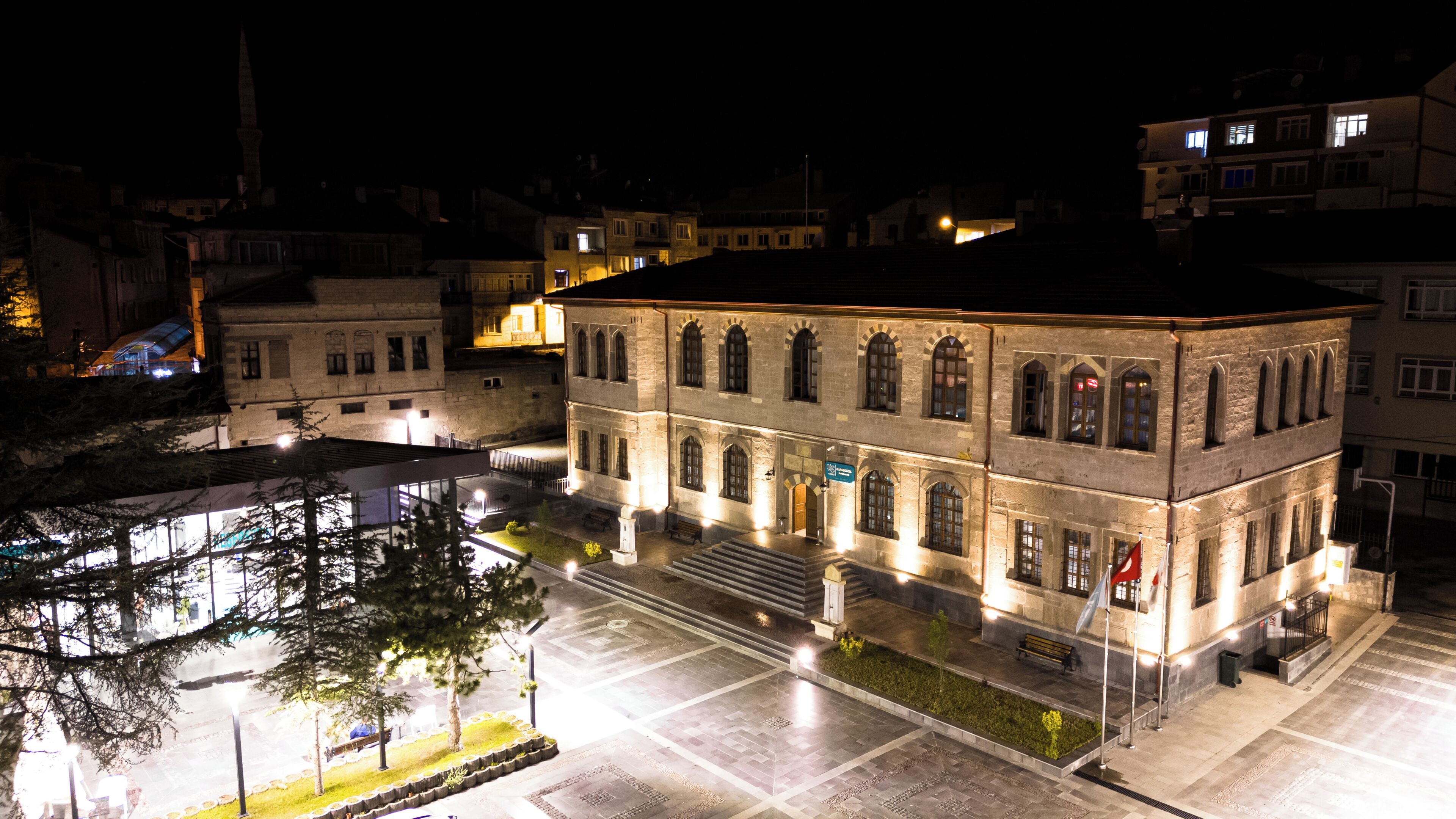 Um edifício histórico com um pátio central, uma bandeira e uma entrada bem iluminada.