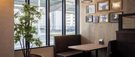 Um interior moderno com um banco de madeira, uma mesa e uma planta em vaso perto de uma janela grande.