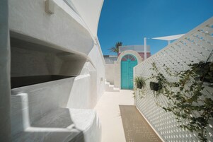 Design arquitetônico moderno com fachada branca, porta azul-turquesa e parede treliçada branca com vegetação.