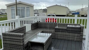 Um terraço coberto ao ar livre com móveis de vime e área para churrasco.