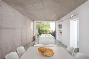 Cozinha moderna com ilha central, armários brancos e vista para um jardim.