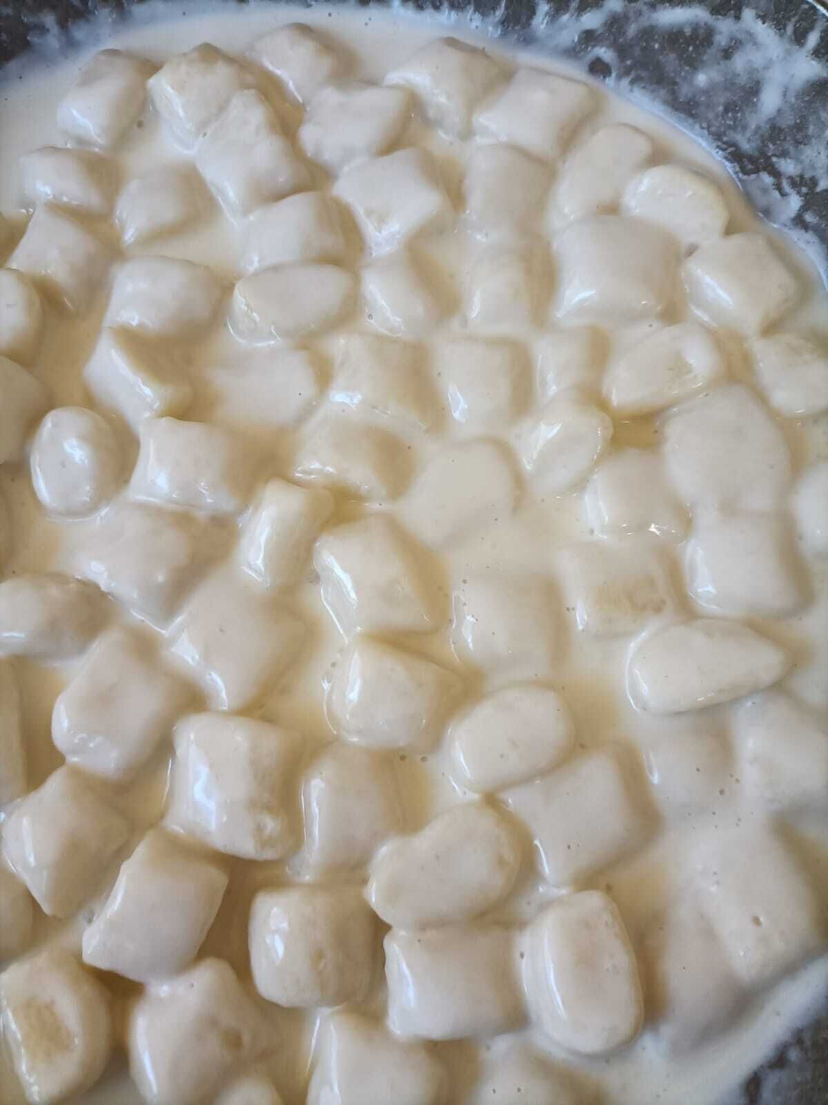 Close-up de uma substância cremosa com pedaços em cubos, provavelmente um preparo de alimento.