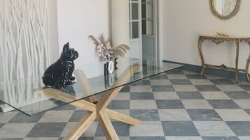 Um quarto espaçoso com uma mesa de vidro, uma estátua decorativa de cachorro e um chão xadrez.