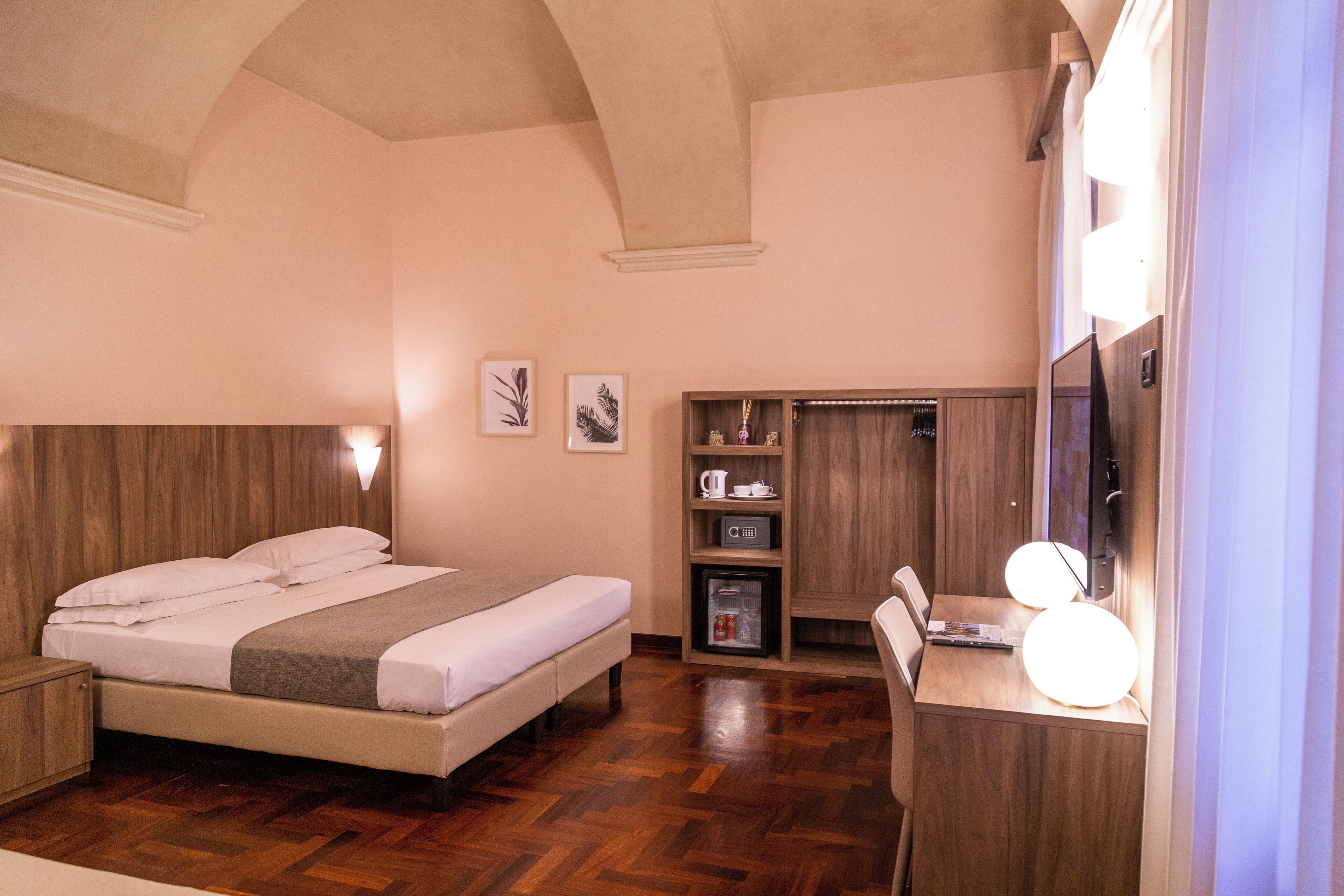 Quarto com cama, mesa de cabeceira, guarda-roupa e toucador com espelho e iluminação.
