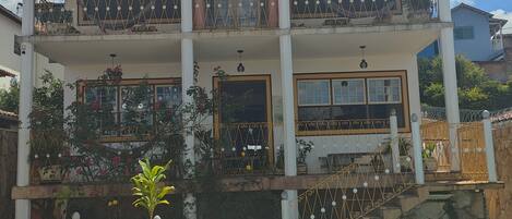 Uma casa de dois andares com varanda, piscina e antena parabólica.
