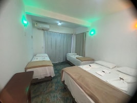 Quarto de hotel com duas camas de solteiro, uma escrivaninha e uma cadeira.