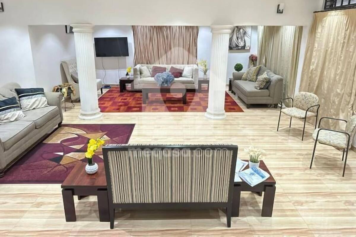 Uma sala de estar moderna com um sofá, uma mesa de centro e uma TV fixada na parede.
