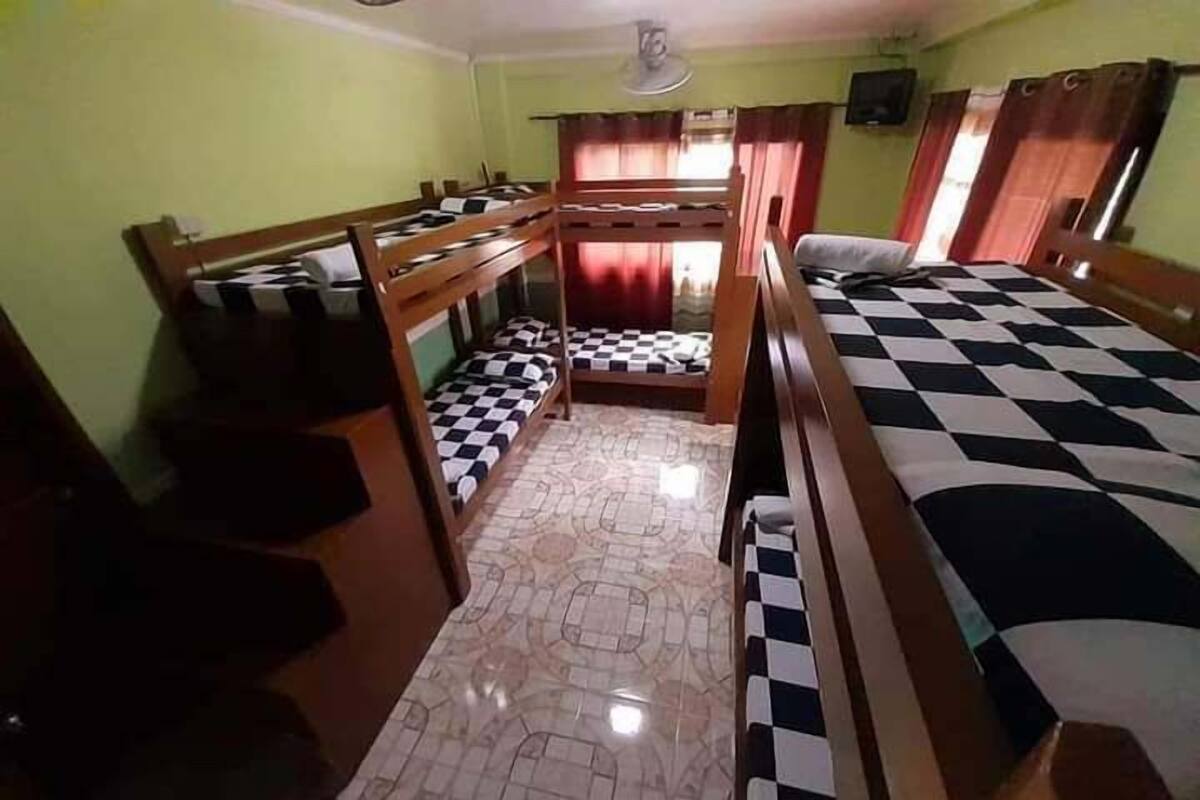 Um dormitório com beliches, piso de azulejos e ventilador de teto.