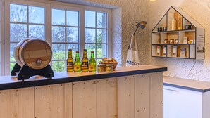 Uma área de bar com balcão de madeira, garrafas e um barril.