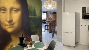Uma cozinha moderna com uma grande pintura da Mona Lisa, uma área de jantar com mesa redonda e um balcão com banquetas.