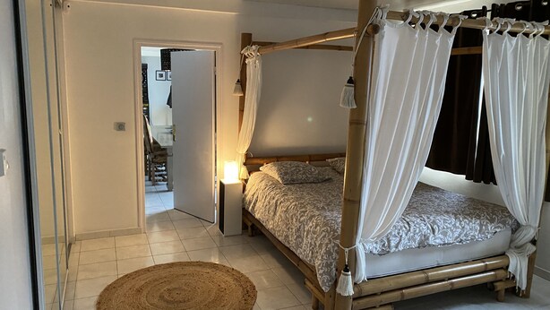 Um quarto com uma cama de dossel, um abajur e um tapete tecido no chão.