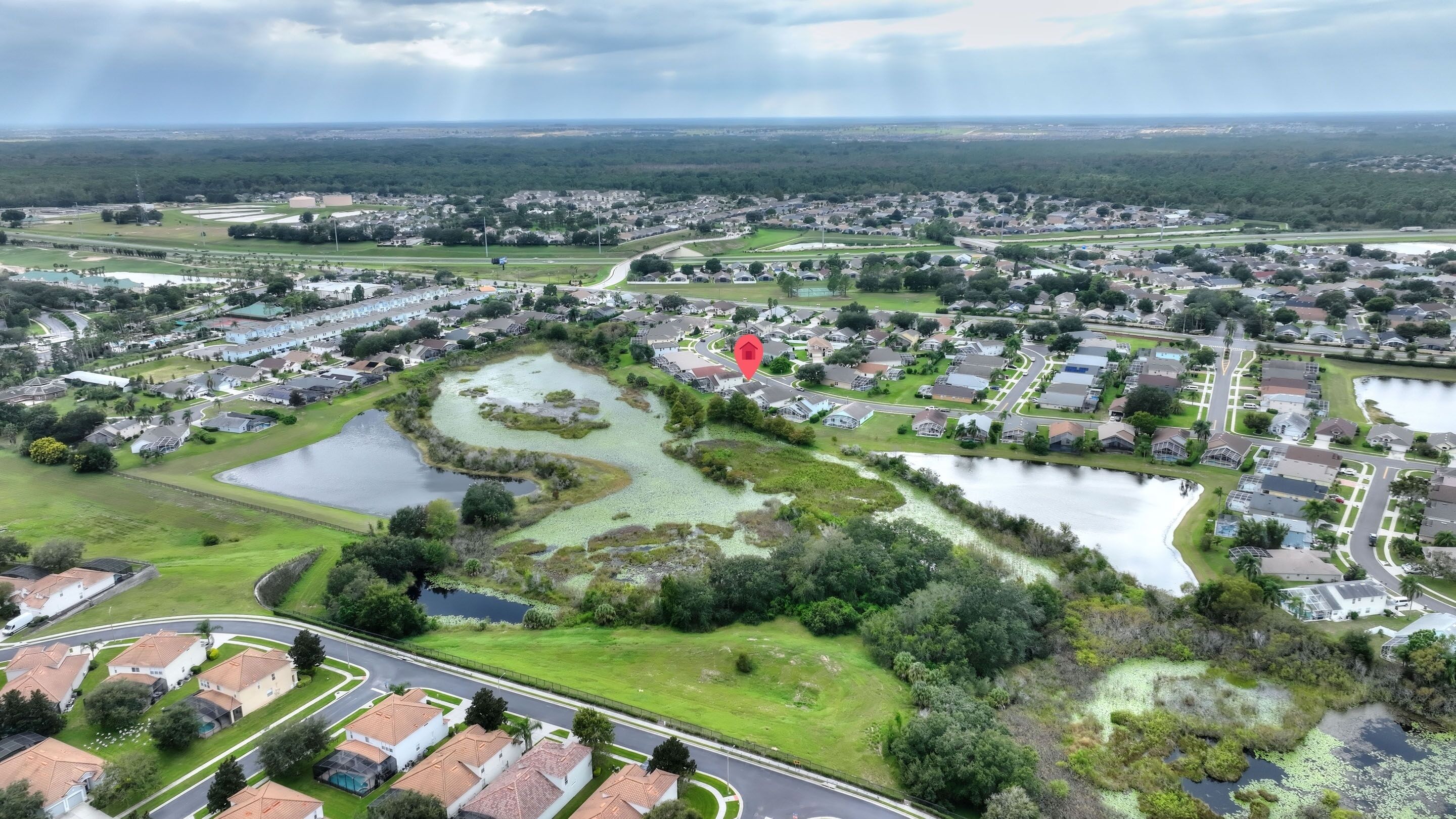 Vista aérea de um bairro residencial com casas, ruas e um lago grande.