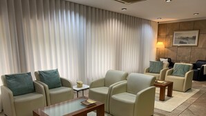 Uma sala de estar moderna com sofás bege, uma mesa de centro de vidro e piso ladrilhado.