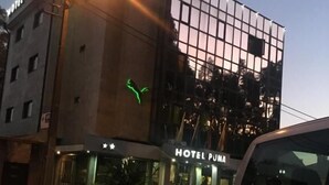 Um edifício com placa 'HOTEL PUMA', um logotipo verde e estilo arquitetônico moderno.