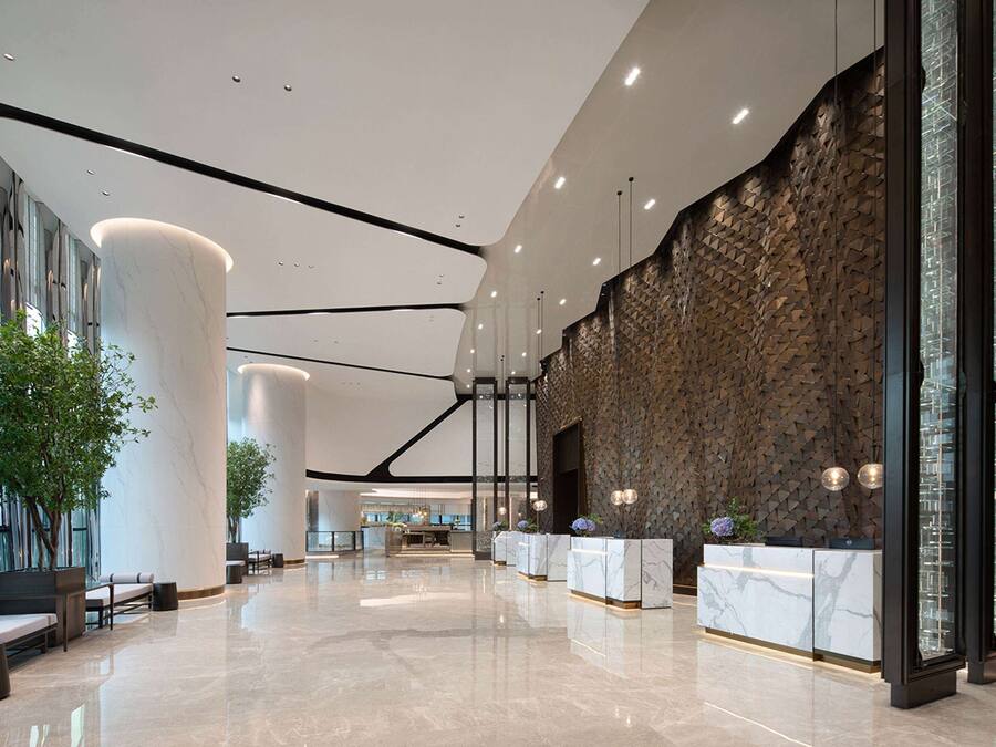 Um hall amplo com balcão de recepção, área de estar e parede decorativa.