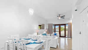 Uma área de refeições moderna e bem iluminada, com mobiliário branco e um candelabro.