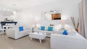 Uma sala de estar moderna com um sofá branco, uma mesa de centro e um espaço de jantar com uma mesa e cadeiras brancas.