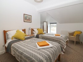 Quarto com duas camas, uma cadeira e um espelho.