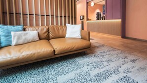 Uma área de recepção moderna, com balcão, sofá com almofadas e um tapete estampado.