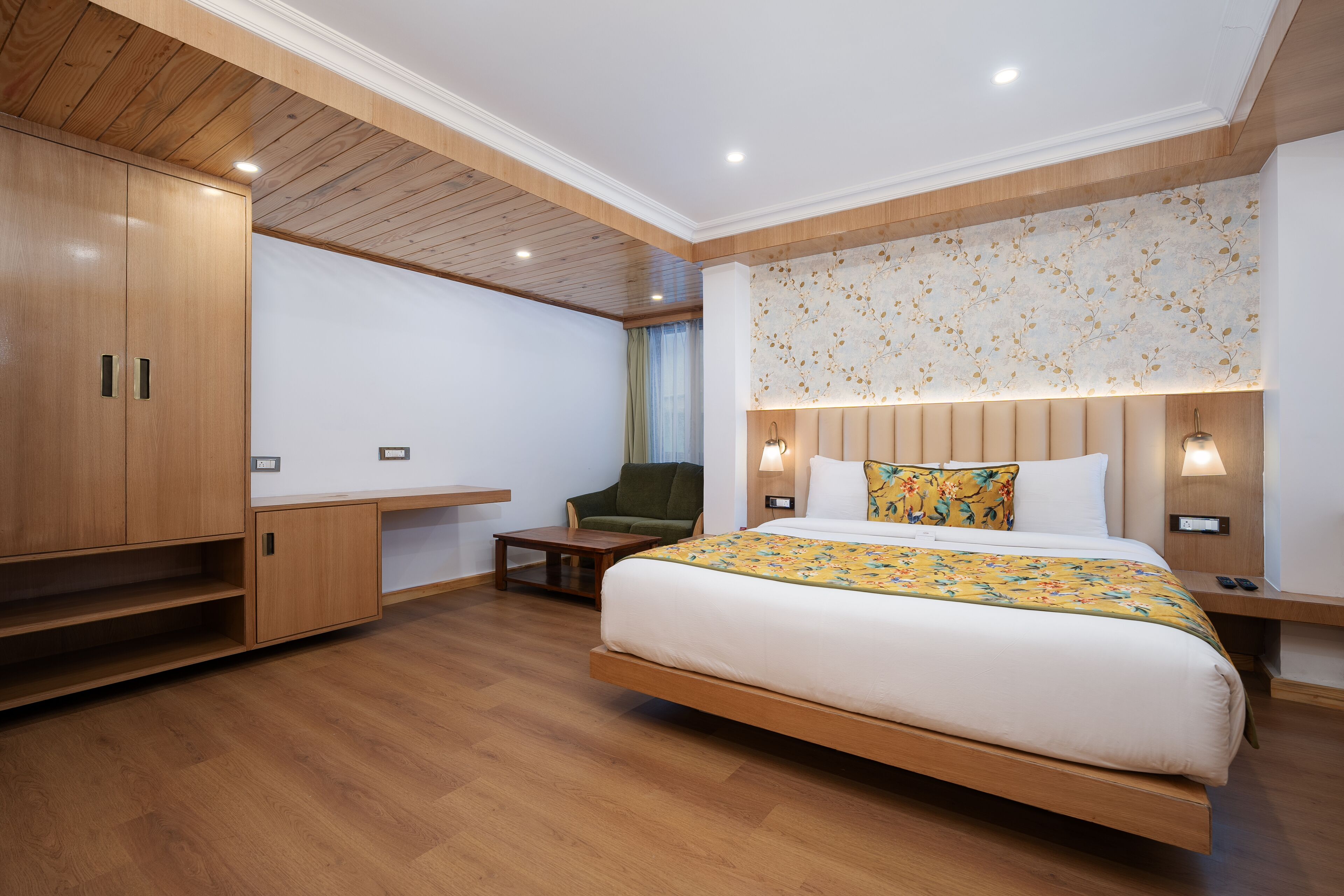 Quarto moderno com uma cama grande, guarda-roupa de madeira, mesas de cabeceira e uma cadeira verde.