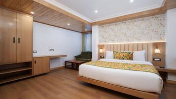 Quarto moderno com uma cama grande, guarda-roupa de madeira, mesas de cabeceira e uma cadeira verde.