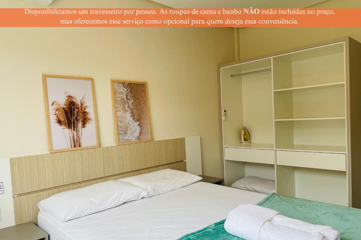 Quarto de hotel com cama, toalha verde e guarda-roupa.