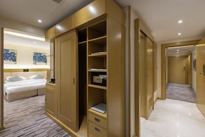 Quarto de hotel com um guarda-roupa grande, uma cama com almofadas e uma escrivaninha com um laptop.