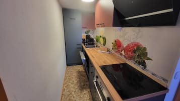 Uma cozinha pequena com bancada de madeira, fogão preto e micro-ondas.