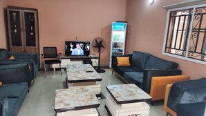 Sala de estar com sofás, televisão, frigorífico e armário.
