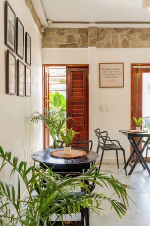 Uma sala de jantar com uma mesa redonda, cadeiras e plantas em vasos.