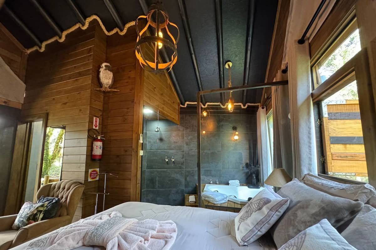 Quarto de cabana de madeira aconchegante, com cama, chuveiro e vista para o exterior.