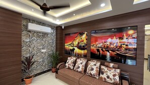 Um lobby moderno com um sofá marrom, duas pinturas grandes, um ventilador de teto e uma parede com padrão.