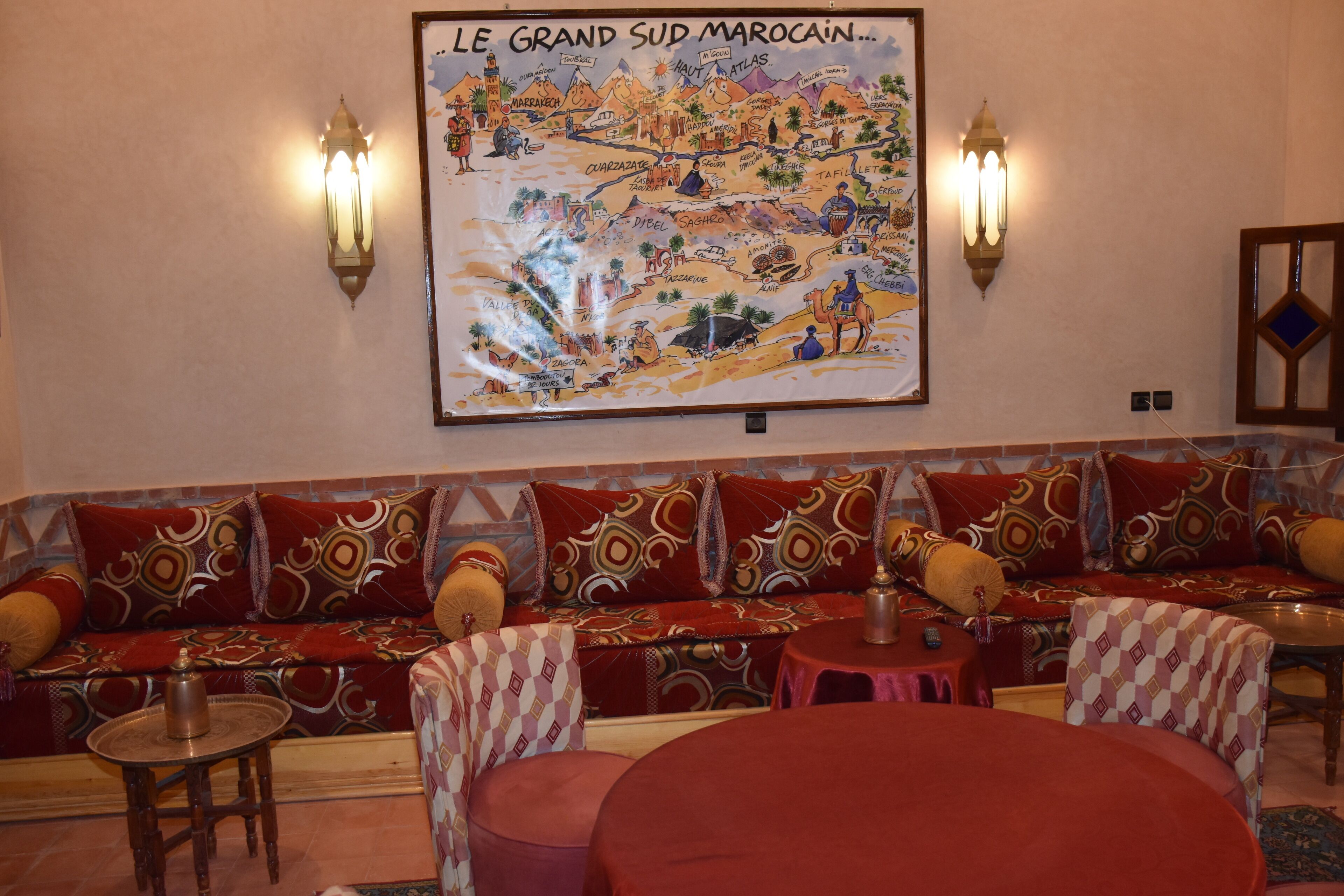 Quarto com decoração marroquina, apresentando um grande mapa mural, sofá estampado e iluminação em estilo tradicional marroquino.