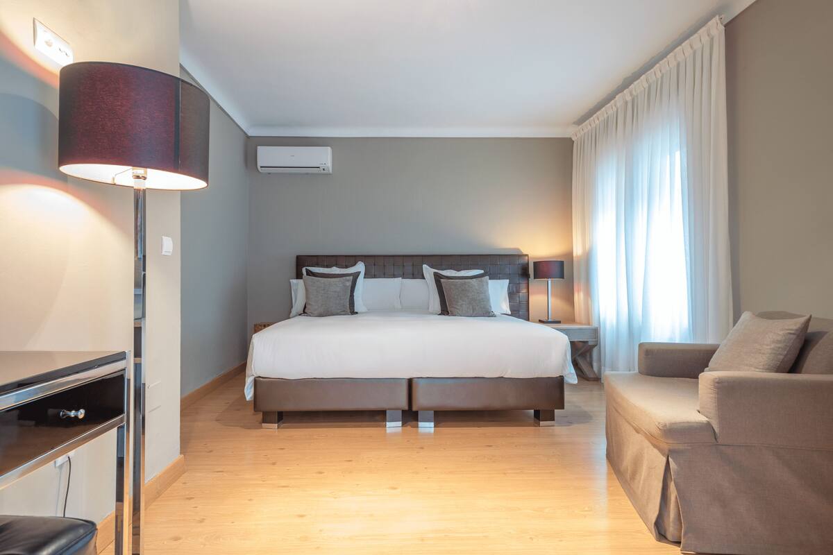 Quarto de hotel com cama, escrivaninha, cadeira e abajur.