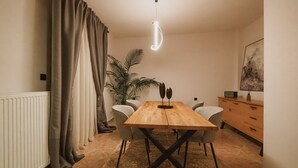 Uma área de refeições moderna com uma mesa de madeira, cadeiras cinzas, uma pequena planta em vaso e decoração minimalista.