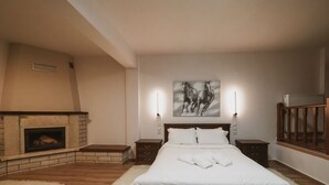 Um quarto com uma cama grande, lareira, tapete fofo e um quadro na parede.