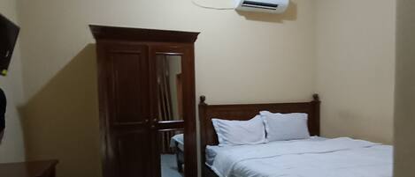 Quarto com cama, guarda-roupa e ar condicionado.