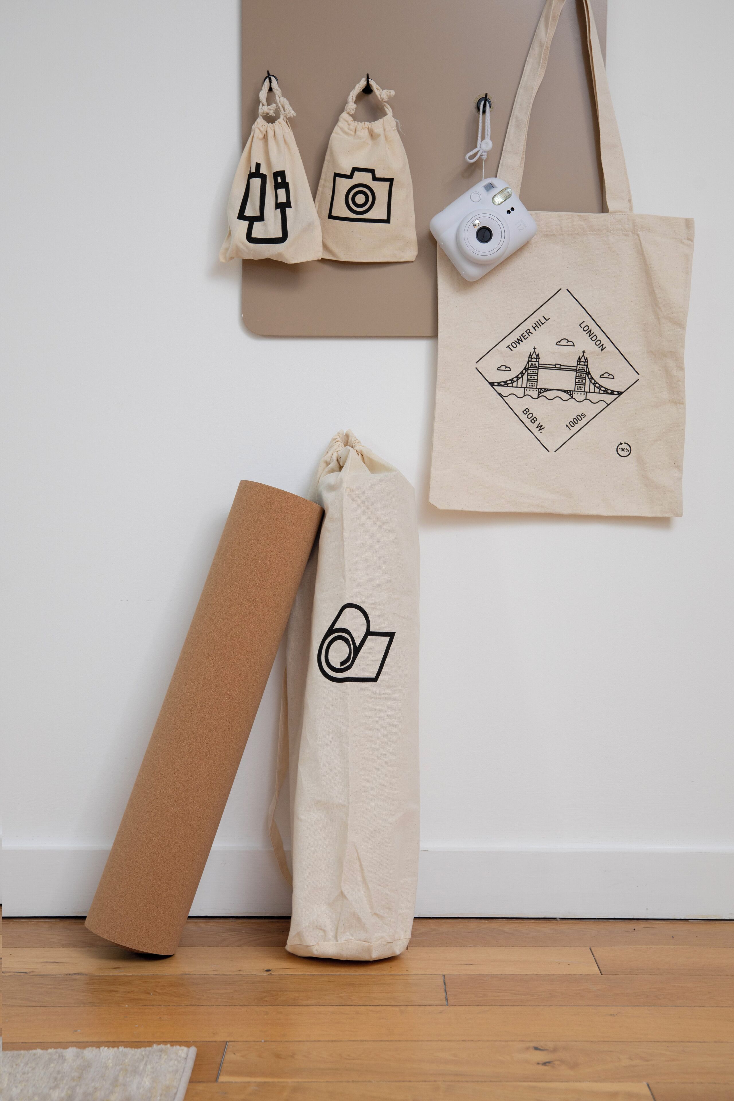 Um tapete de yoga, duas sacolas com cordão e uma câmera na parede.