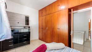 Quarto com cama, guarda-roupa de madeira e porta para uma varanda.