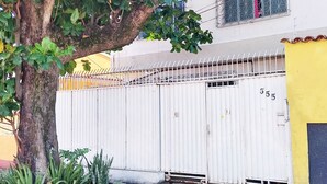 Uma área cercada com uma árvore e um edifício ao fundo.