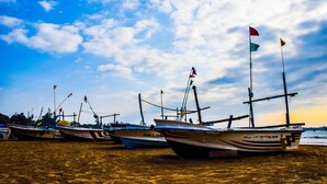 Vários barcos atracados numa praia arenosa com céu claro.