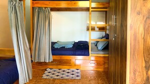 Quarto compacto com beliches, sofá e guarda-roupa de madeira.