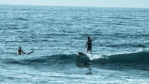 Cena de praia com dois surfistas na água.