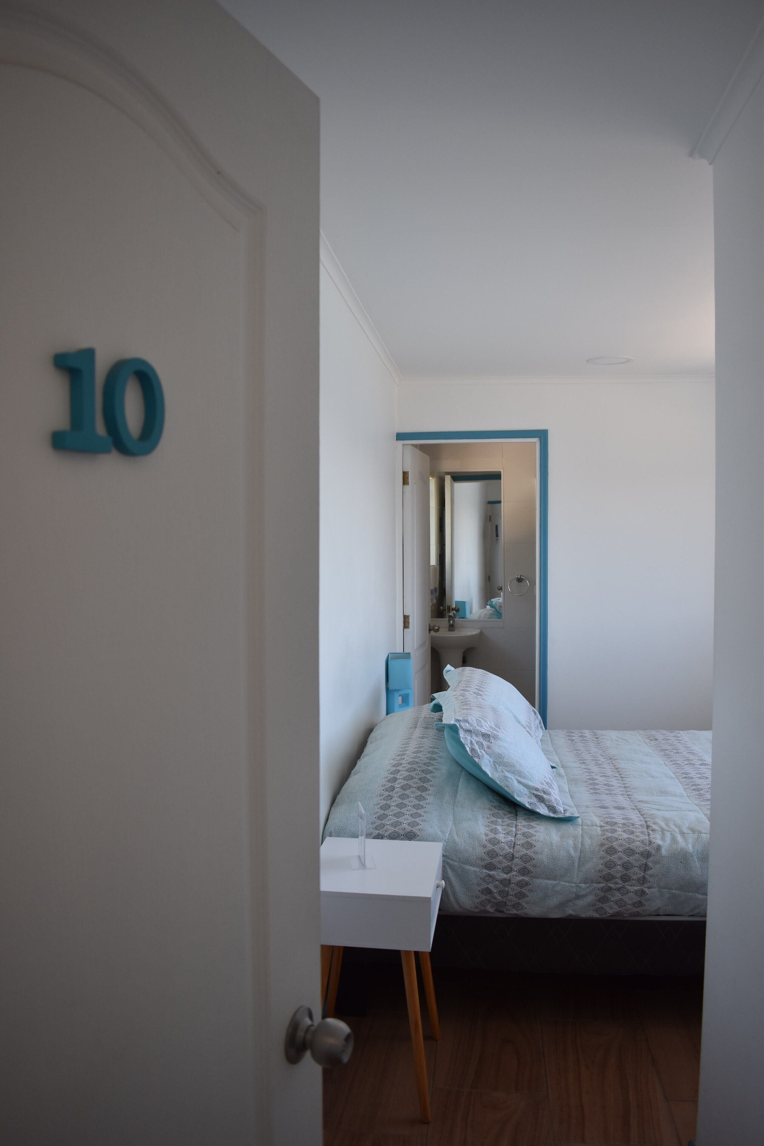 Quarto com uma cama, mesa de cabeceira, espelho e porta com o número 10.