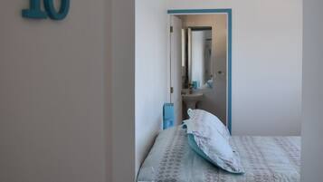 Quarto com uma cama, mesa de cabeceira, espelho e porta com o número 10.