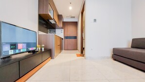 Uma sala de estar moderna com televisão de tela plana, um sofá e uma área de cozinha ao fundo.