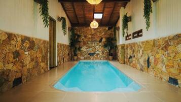 Piscina com paredes de pedra e teto de madeira.