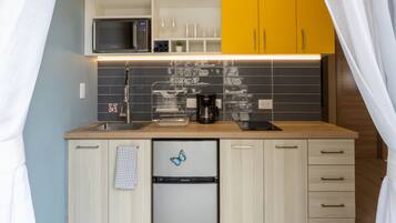 Uma cozinha compacta com micro-ondas, cafeteira e geladeira com um ímã de borboleta.