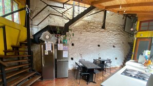 Uma cozinha rústica com escada de madeira, geladeira e um espaço de jantar com mesa e cadeiras.